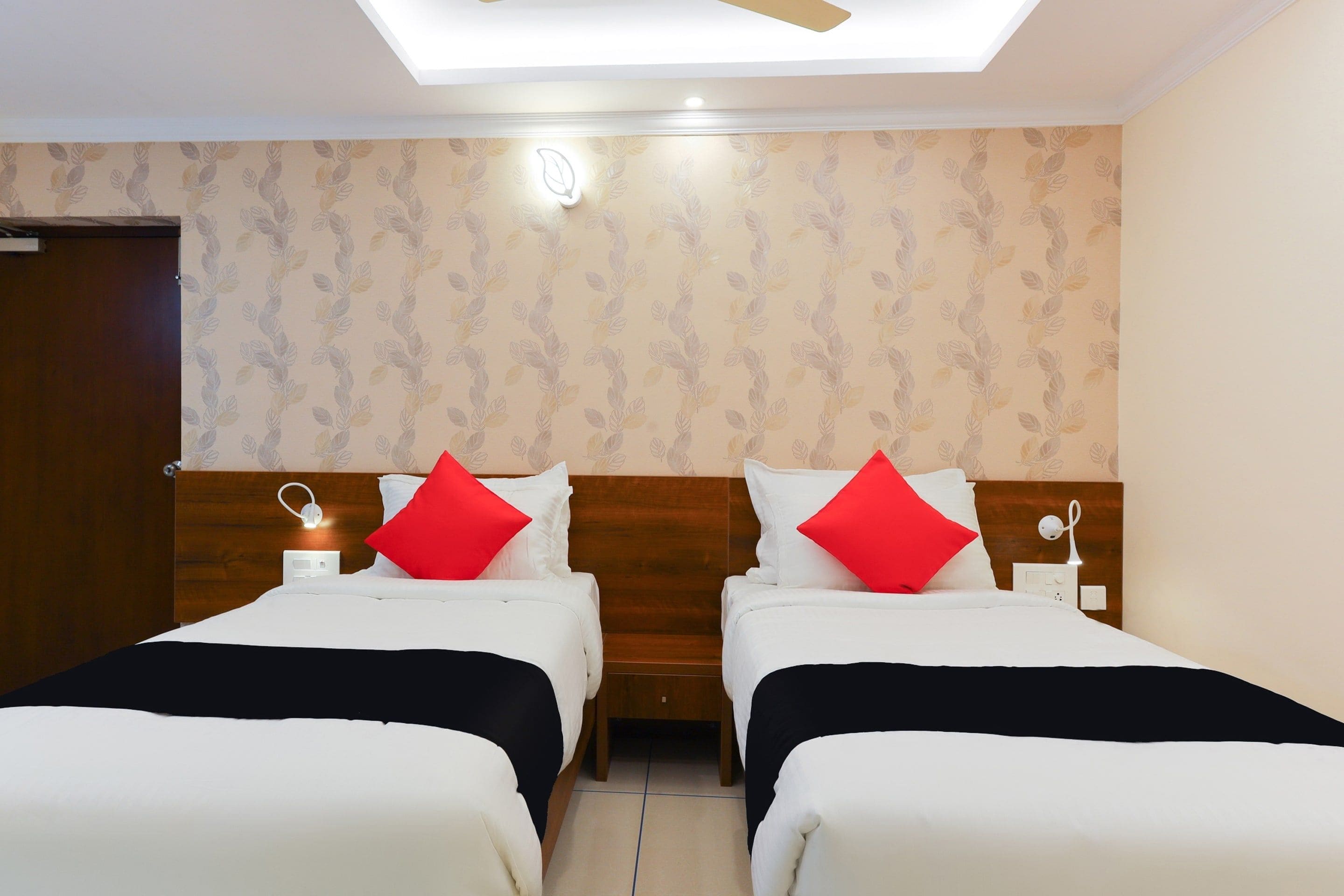 Quarto de hotel com duas camas, um ventilador de teto e uma mesa de cabeceira com abajur.