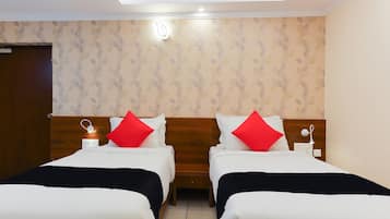 Quarto de hotel com duas camas, um ventilador de teto e uma mesa de cabeceira com abajur.