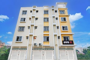 Um prédio de hotel com várias andares, varandas, aparelhos de ar condicionado e uma placa grande do OYO Grand Inn.