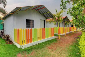 Um edifício térreo com fachada branca, telhado de metal e cerca colorida.