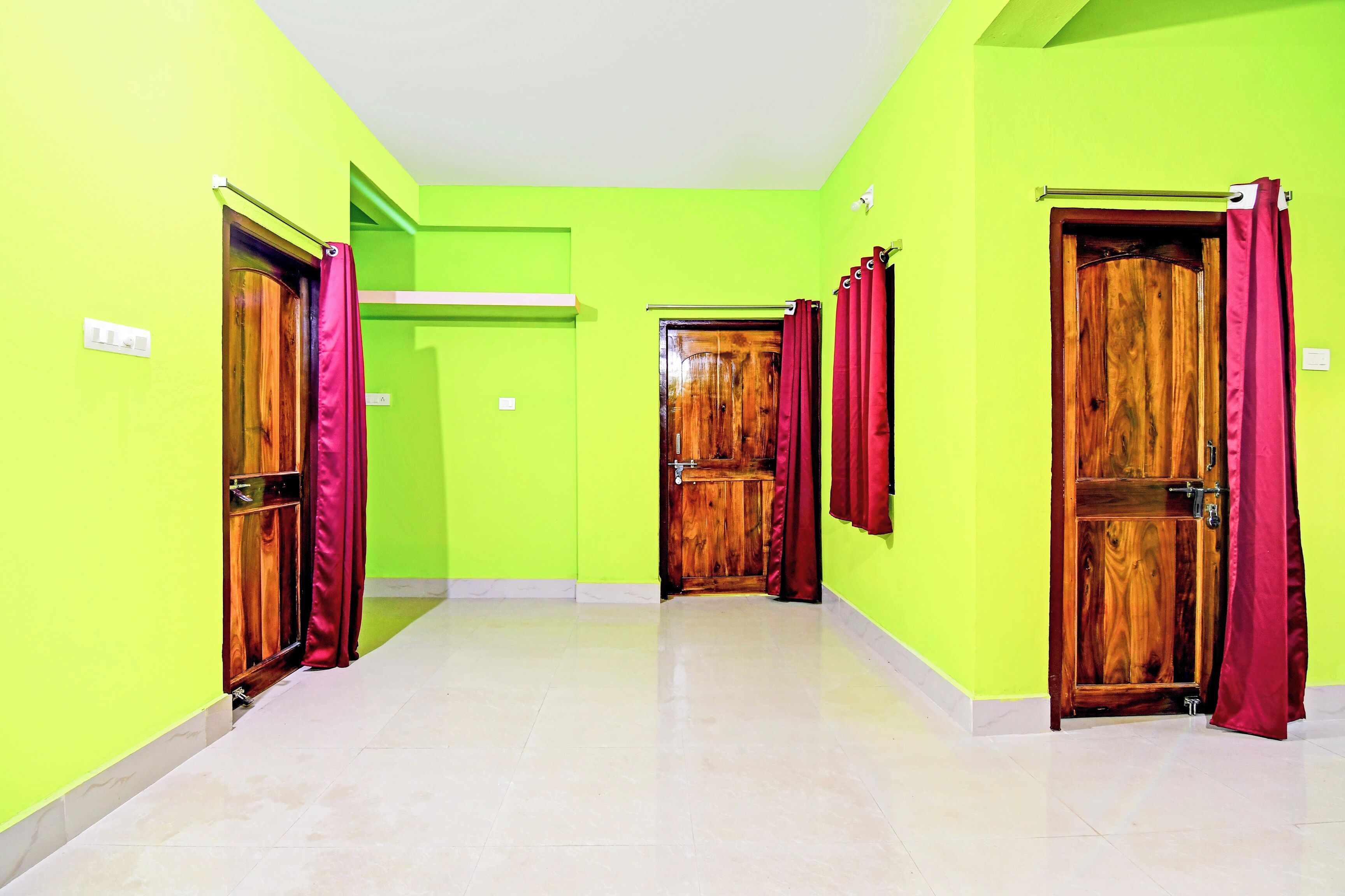 Corredor com portas de madeira e cortinas vermelhas, que dá acesso a um quarto com porta de madeira.