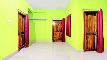 Corredor com portas de madeira e cortinas vermelhas, que dá acesso a um quarto com porta de madeira.