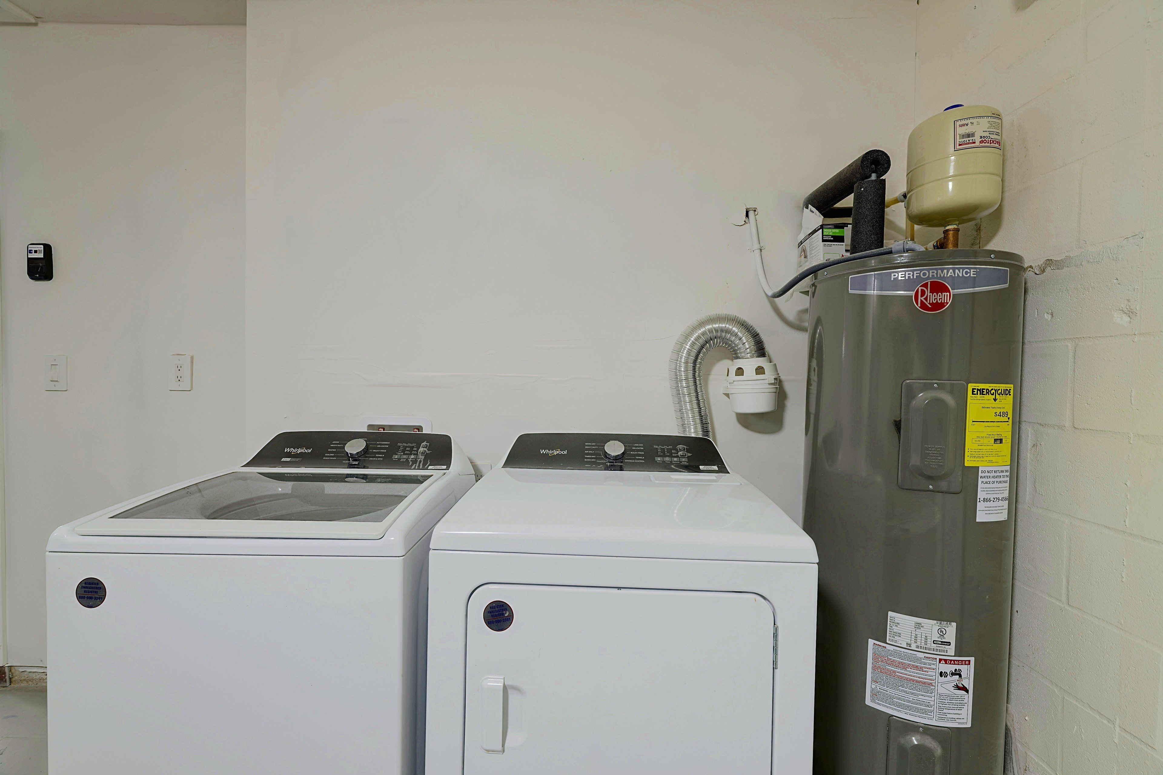 Uma lavanderia com duas máquinas de lavar Whirlpool e um aquecedor de água Rheem.