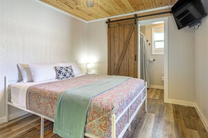Um quarto com uma cama, teto de madeira, porta e janela.