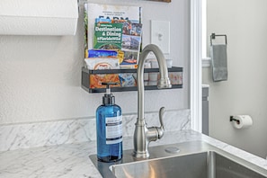 Uma pia de cozinha com uma torneira moderna, um dosador de detergente e um guia de viagens pendurado na parede.