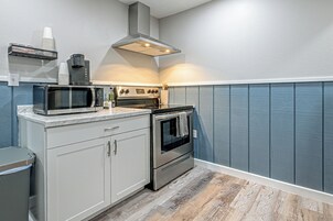 Cozinha compacta com micro-ondas, fogão e cafeteira na bancada.