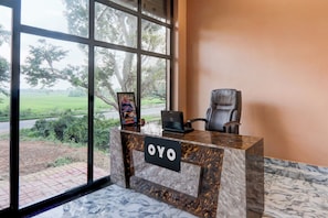 Balcão de recepção com um laptop, uma foto emoldurada e uma placa com a inscrição 'OYO'.