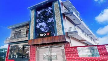 Hotel com fachada de tijolos vermelhos e design arquitetônico moderno, destacando uma placa vertical.