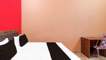 Quarto de hotel com cama, mesa de cabeceira e uma cadeira.