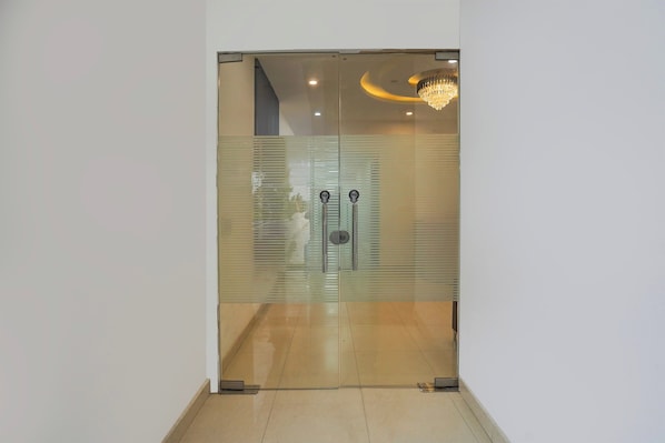 Interior moderno com porta de vidro fosco, puxador e lustre.