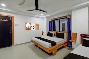 Quarto de hotel com cama, ventilador de teto, janela com cortinas e obras de arte na parede.