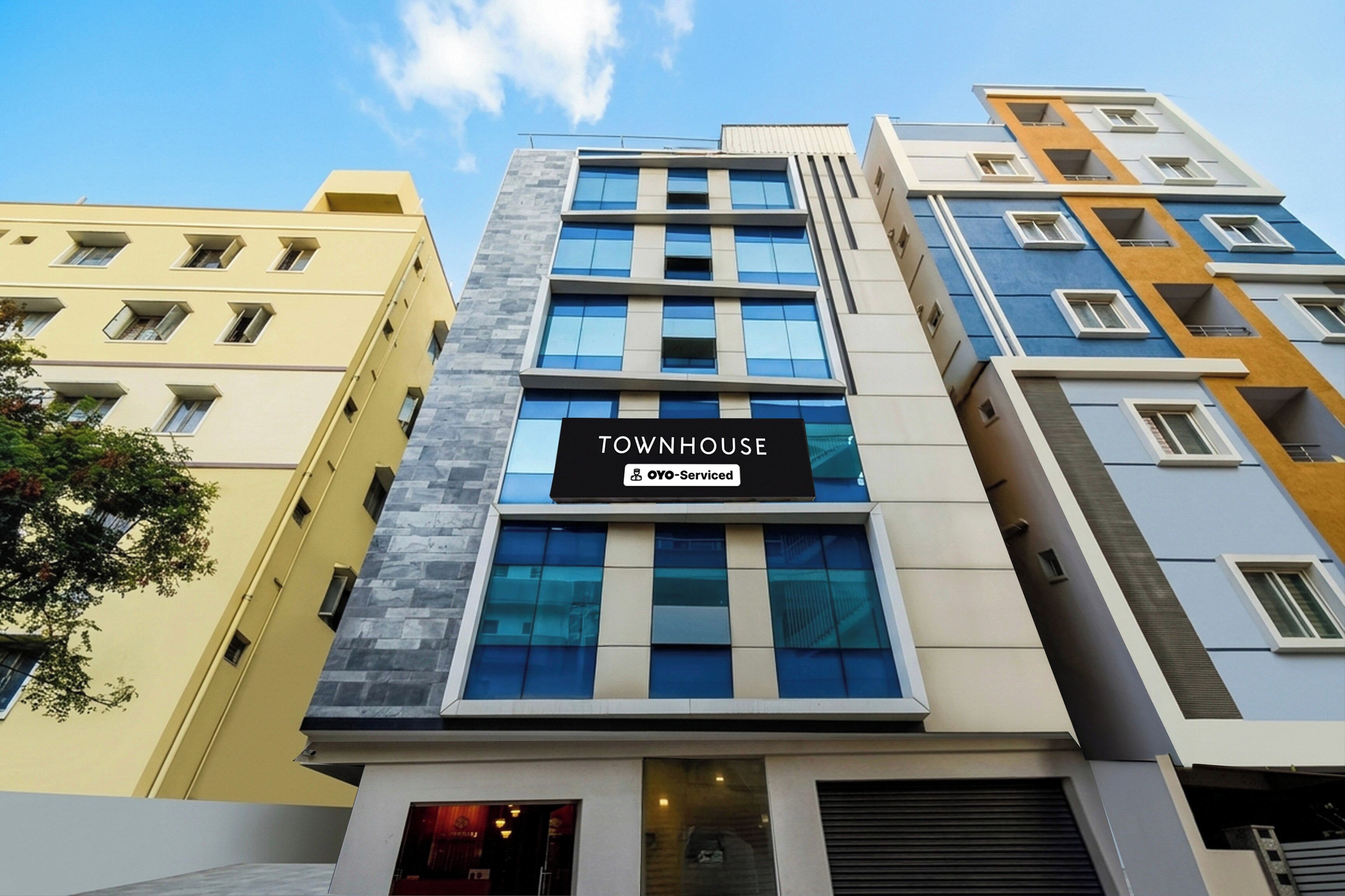 Um edifício de vários andares com uma placa que diz 'TOWNHOUSE' e 'YOYO-Serviced'.