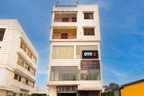 Um hotel de vários andares com varandas e uma placa com a inscrição 'OYO Hotel The Crown'.