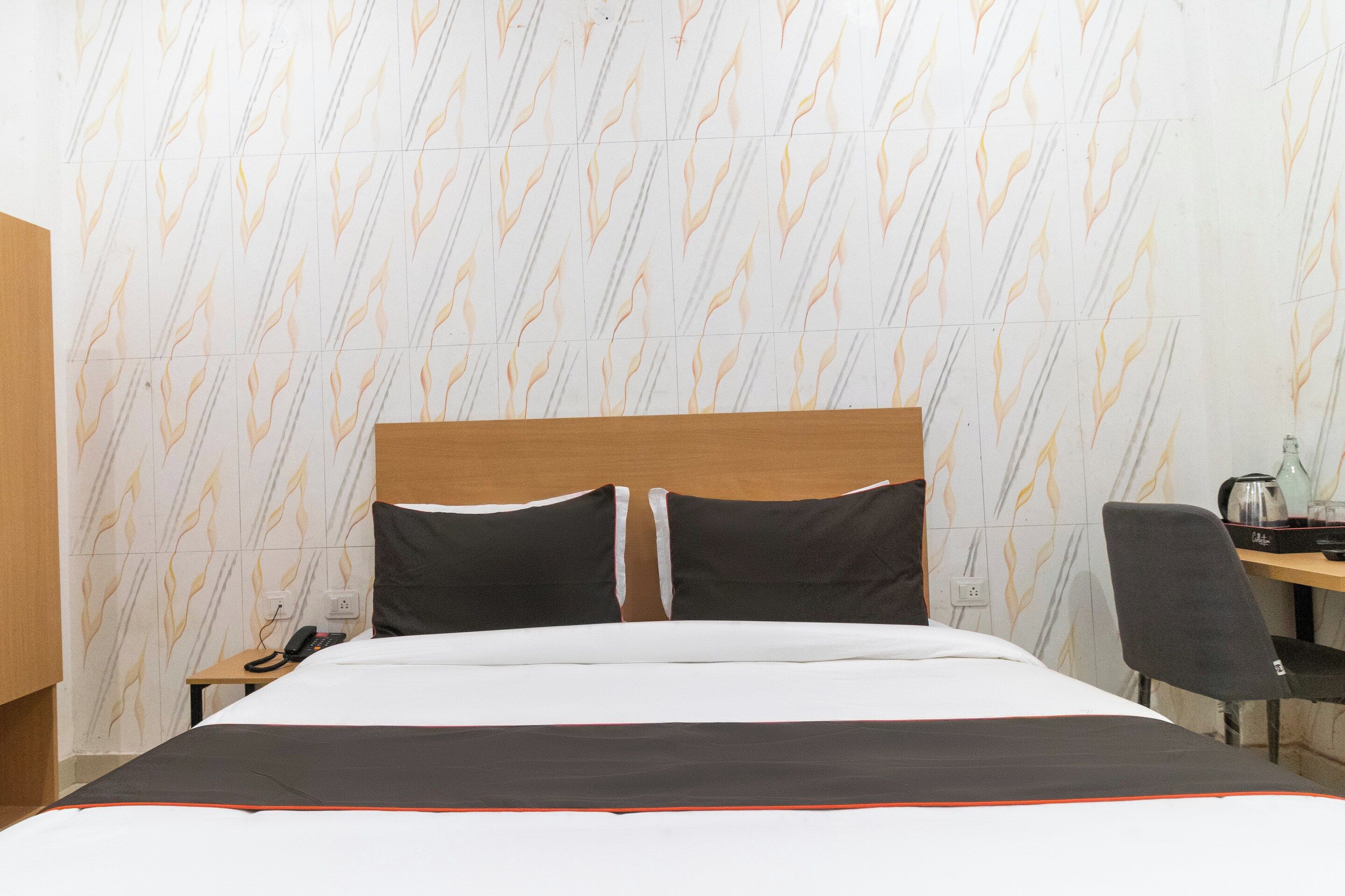 Quarto de hotel com cama, escrivaninha e cadeira.