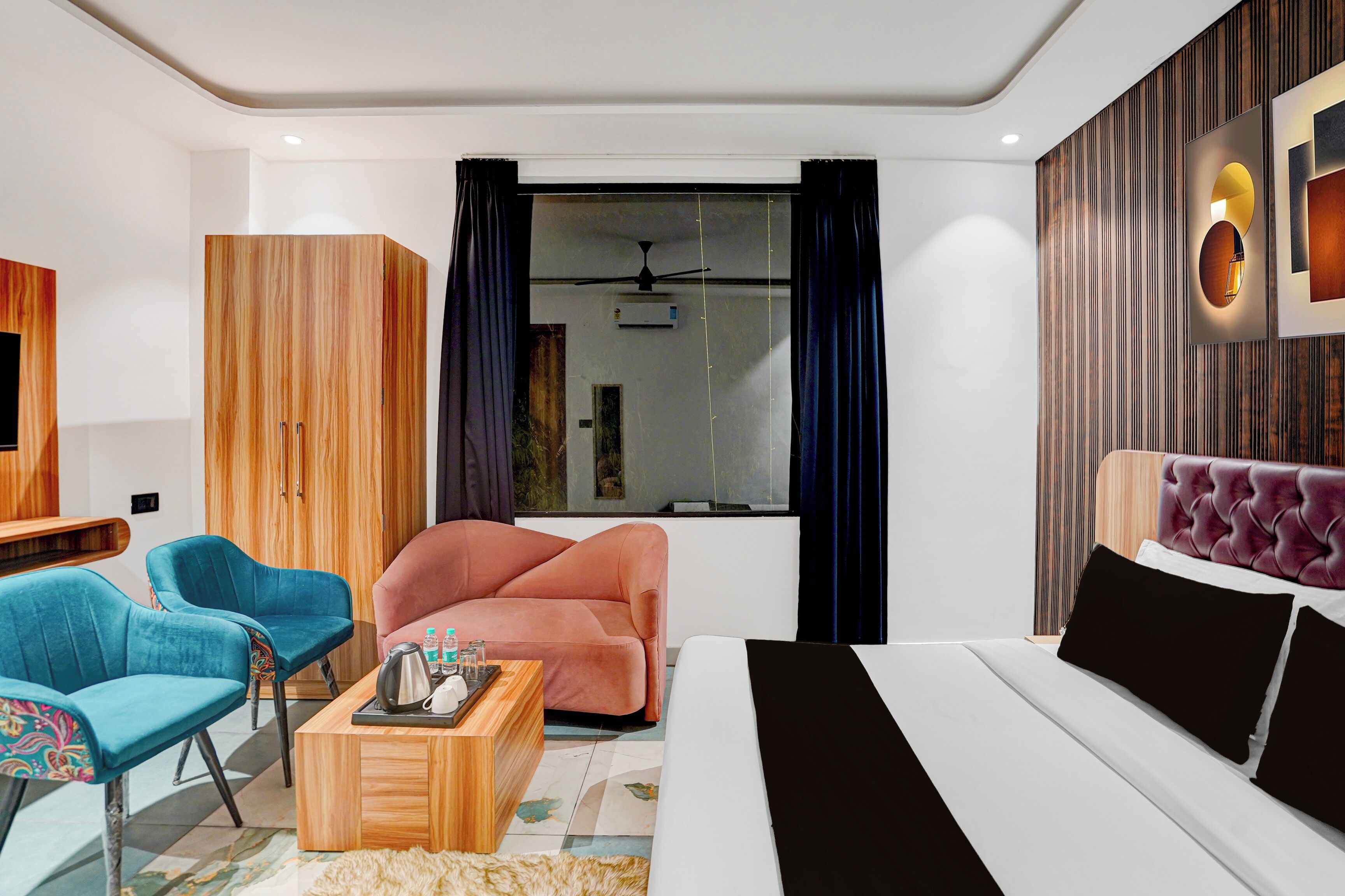 Quarto de hotel moderno com cama, sofá, mesa de centro e televisão.