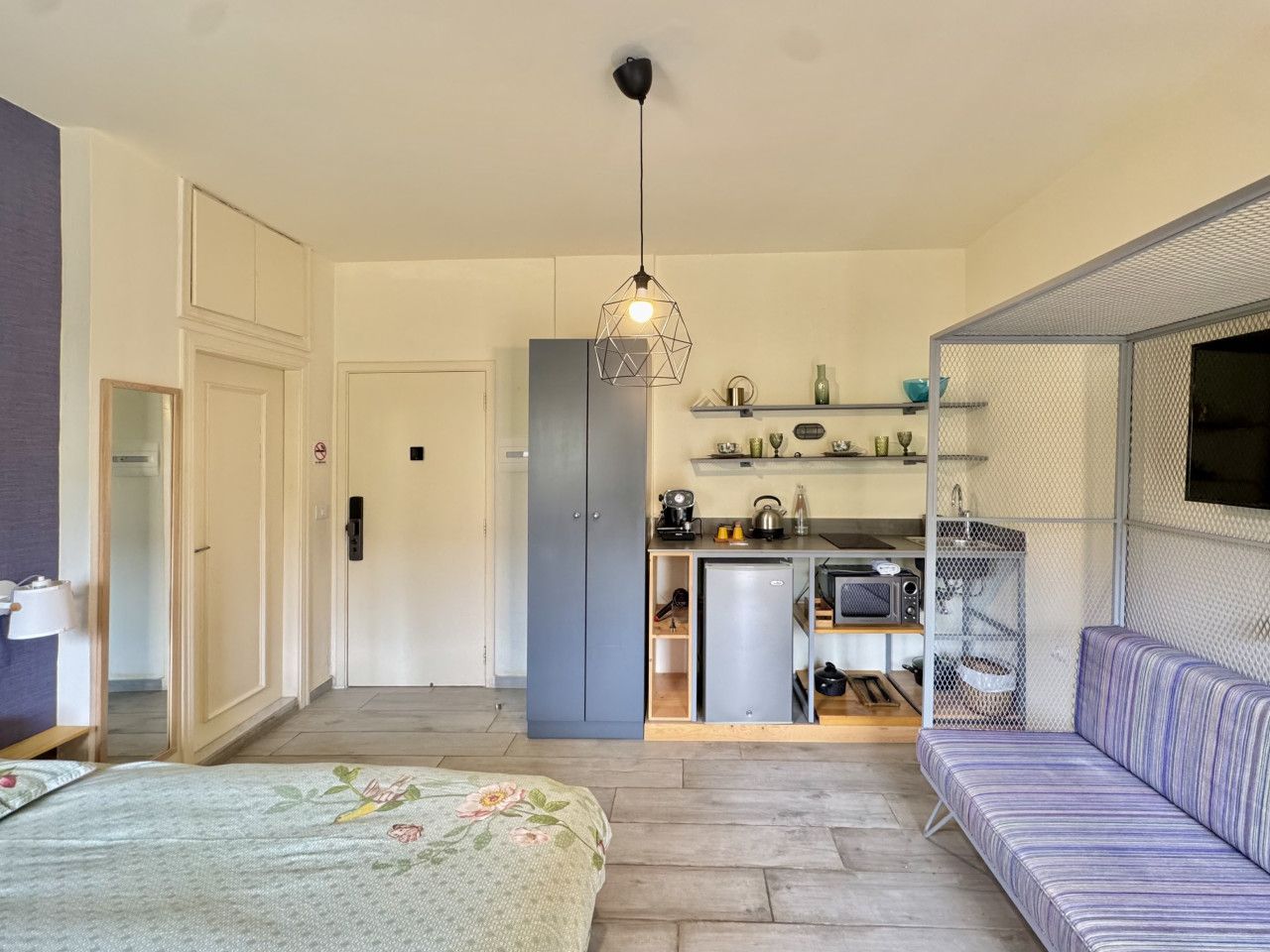 Quarto compacto com cama, sofá, cozinha compacta e área de jantar.