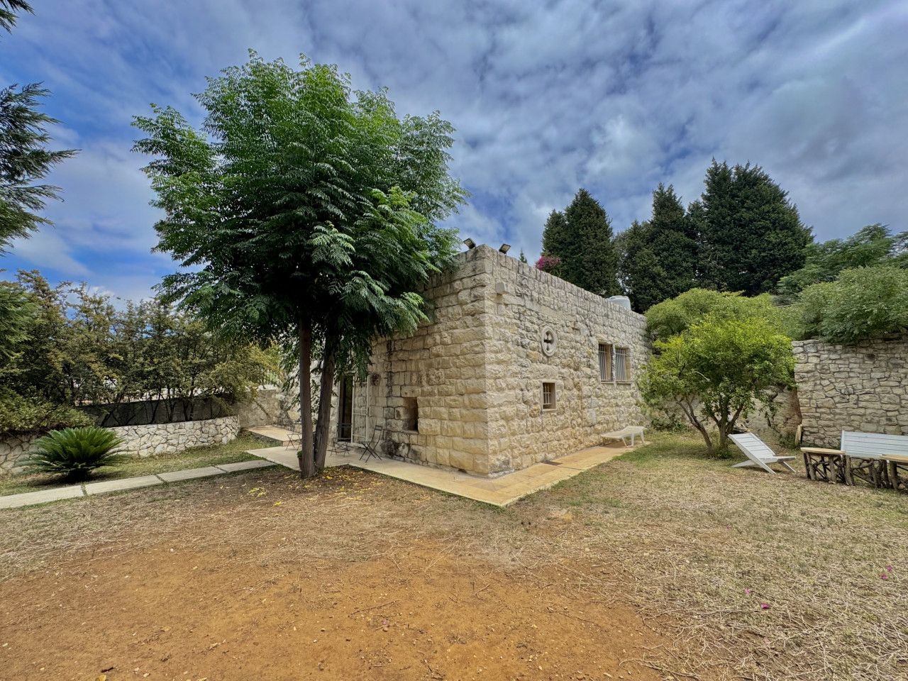 Um edifício de pedra com uma pequena varanda e uma árvore na frente.