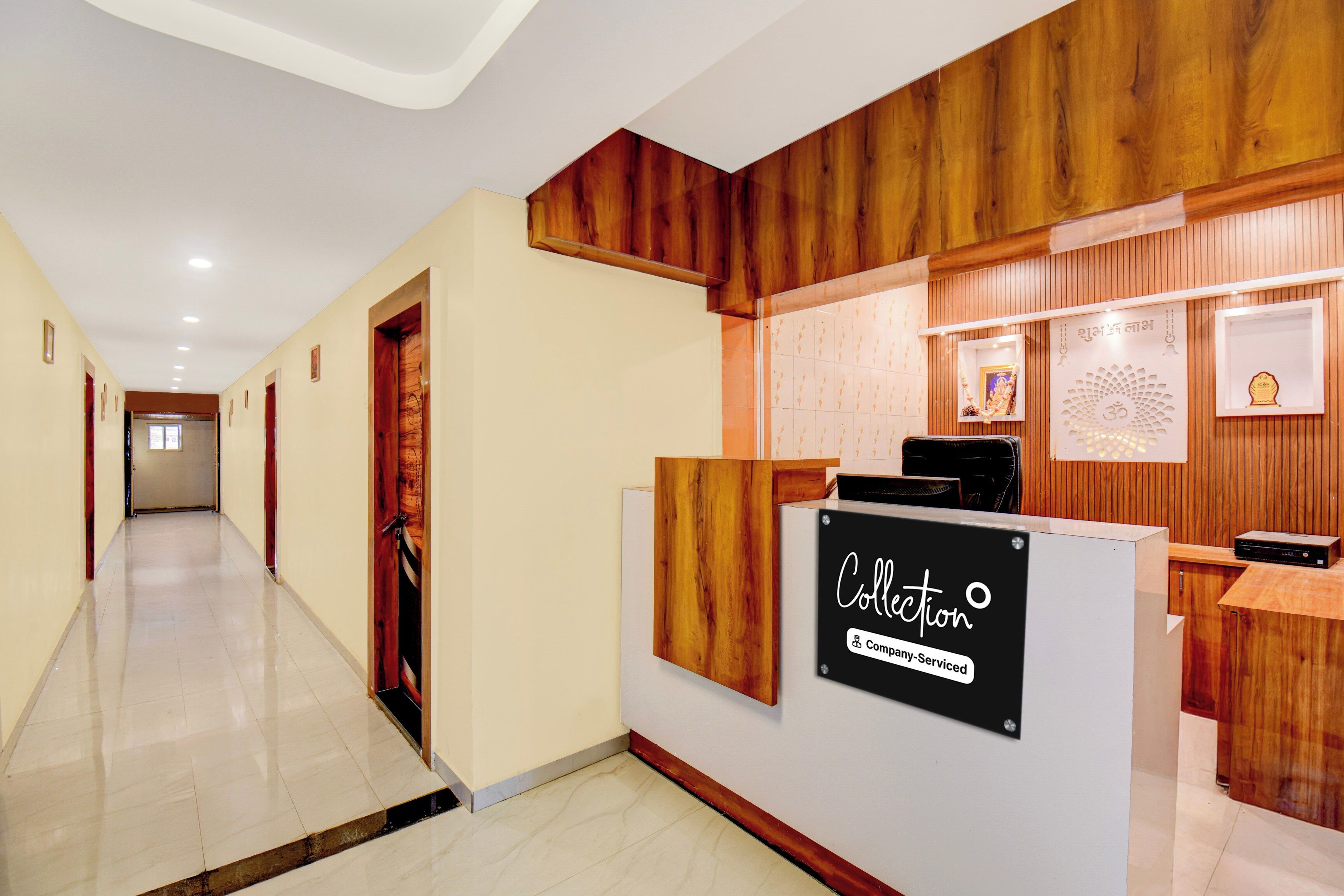 Uma área de recepção com balcão de madeira, placa indicando serviço da empresa, e um corredor que dá acesso a outros quartos.