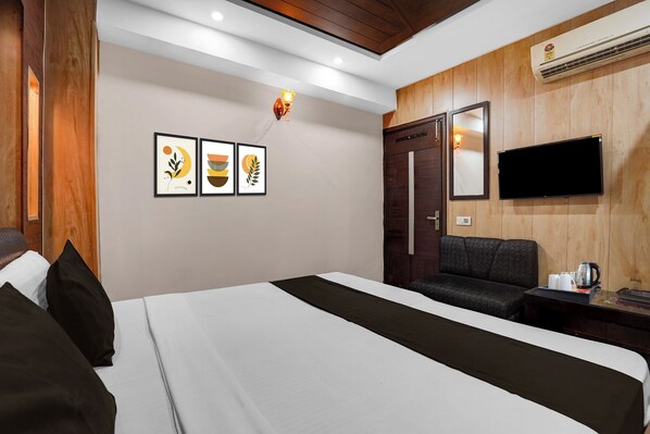 Quarto de hotel com cama, área de estar, TV de tela plana e obras de arte penduradas na parede.