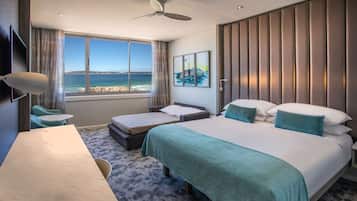 Quarto de hotel com uma cama grande, uma escrivaninha e vista para o mar.