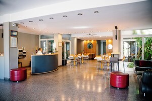 Um hall de hotel com balcão de recepção, área de estar e grandes janelas.