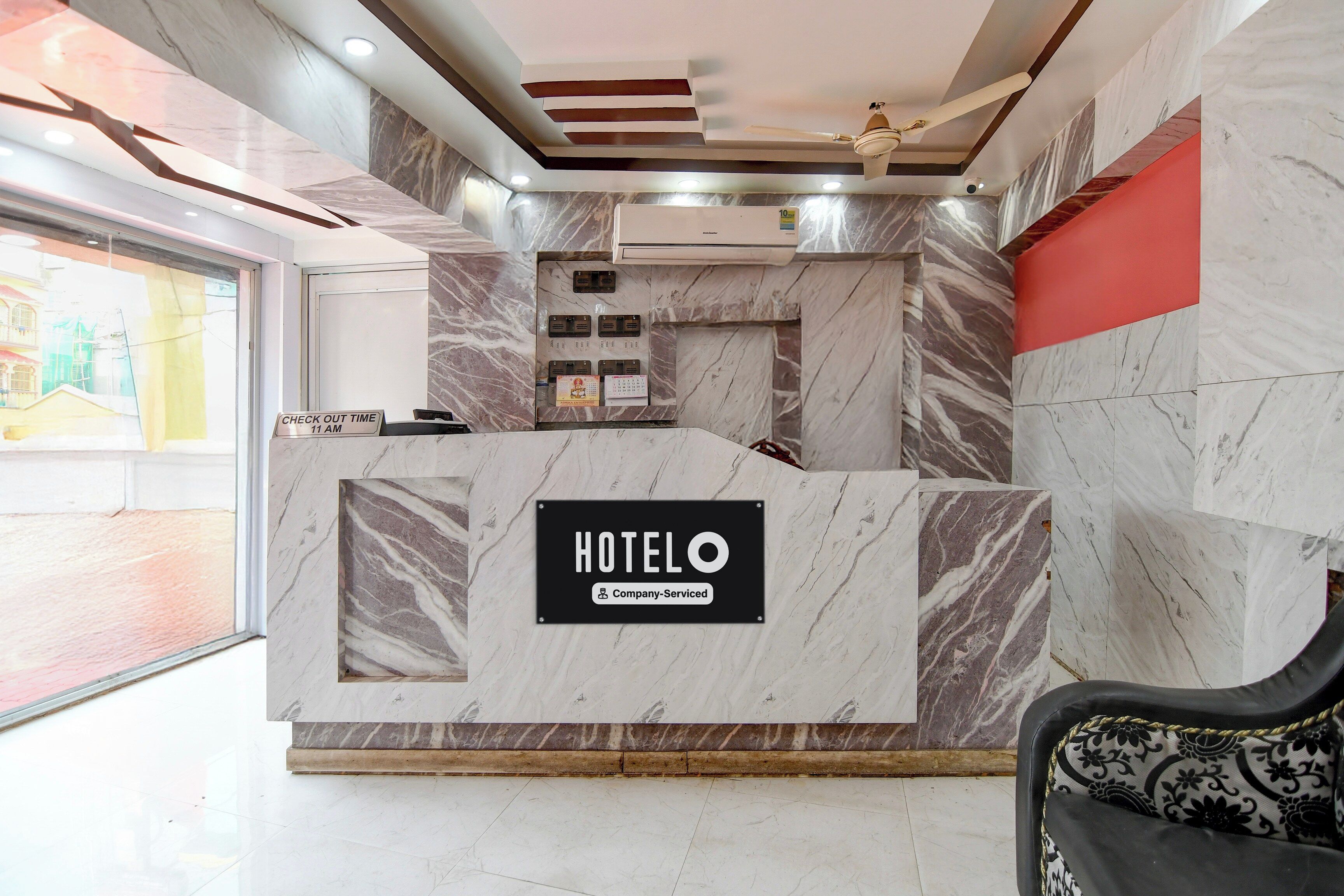 Balcão de recepção de hotel com acabamento em mármore, sinalização do horário de check-out e etiqueta da marca.