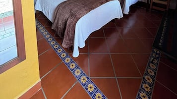 Quarto com duas camas, teto de madeira e piso estampado.