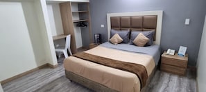 Quarto com cama, mesas de cabeceira, guarda-roupa e escrivaninha.
