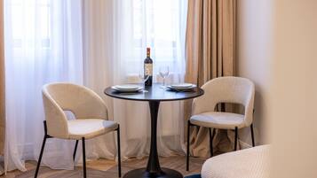 Quarto com uma mesa redonda posta para dois, duas cadeiras, uma garrafa de vinho e um copo sobre a mesa.