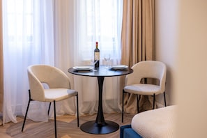 Quarto com uma mesa redonda posta para dois, duas cadeiras, uma garrafa de vinho e um copo sobre a mesa.