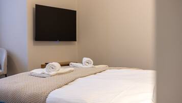 Quarto de hotel com uma cama, televisão de tela plana na parede e uma cadeira.