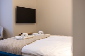 Quarto de hotel com uma cama, televisão de tela plana na parede e uma cadeira.