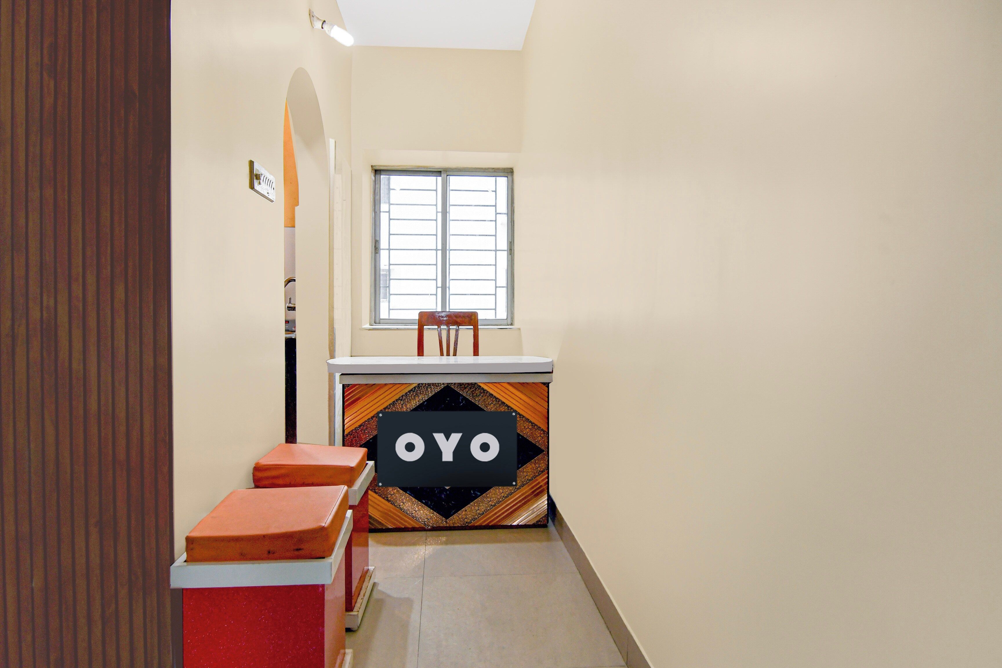 Um corredor estreito com uma janela, um banco e um balcão com uma placa.
