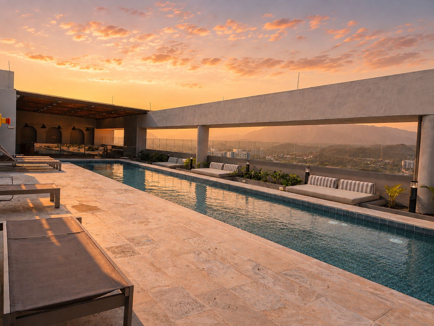Área de piscina no terraço com vista para a paisagem urbana ao pôr do sol.