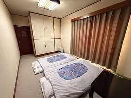 Quarto de hotel com cama, guarda-roupa, aquecedor e janela com cortinas.