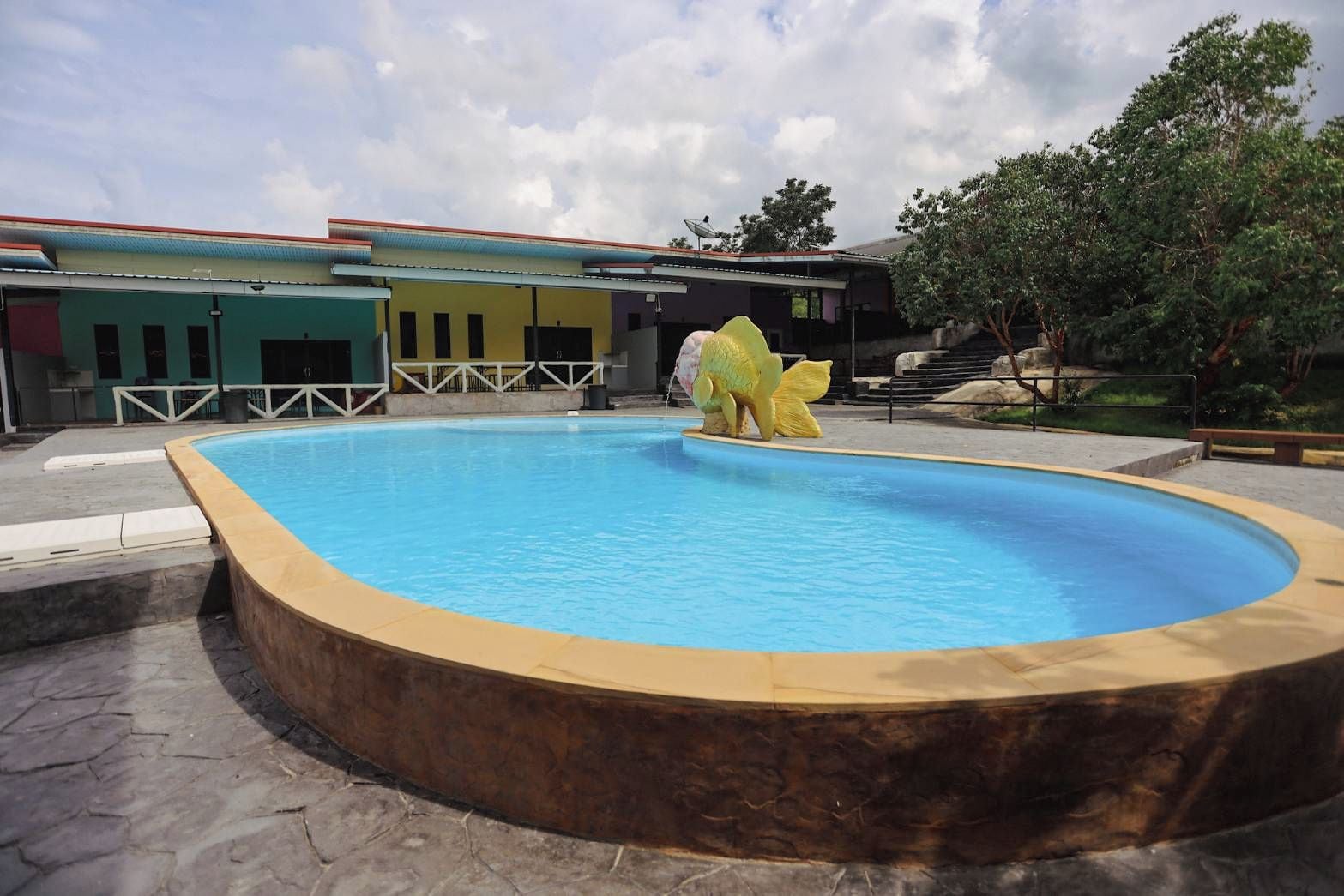 Piscina com borda curva e revestimento de pedra.