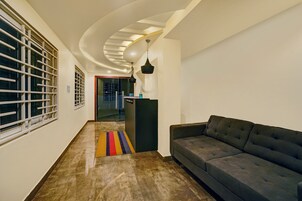 Um interior moderno com teto curvo, um sofá, um tapete colorido e uma área de cozinha.