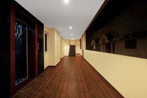 Um corredor extenso com piso de madeira, escada e porta com teclado de segurança.