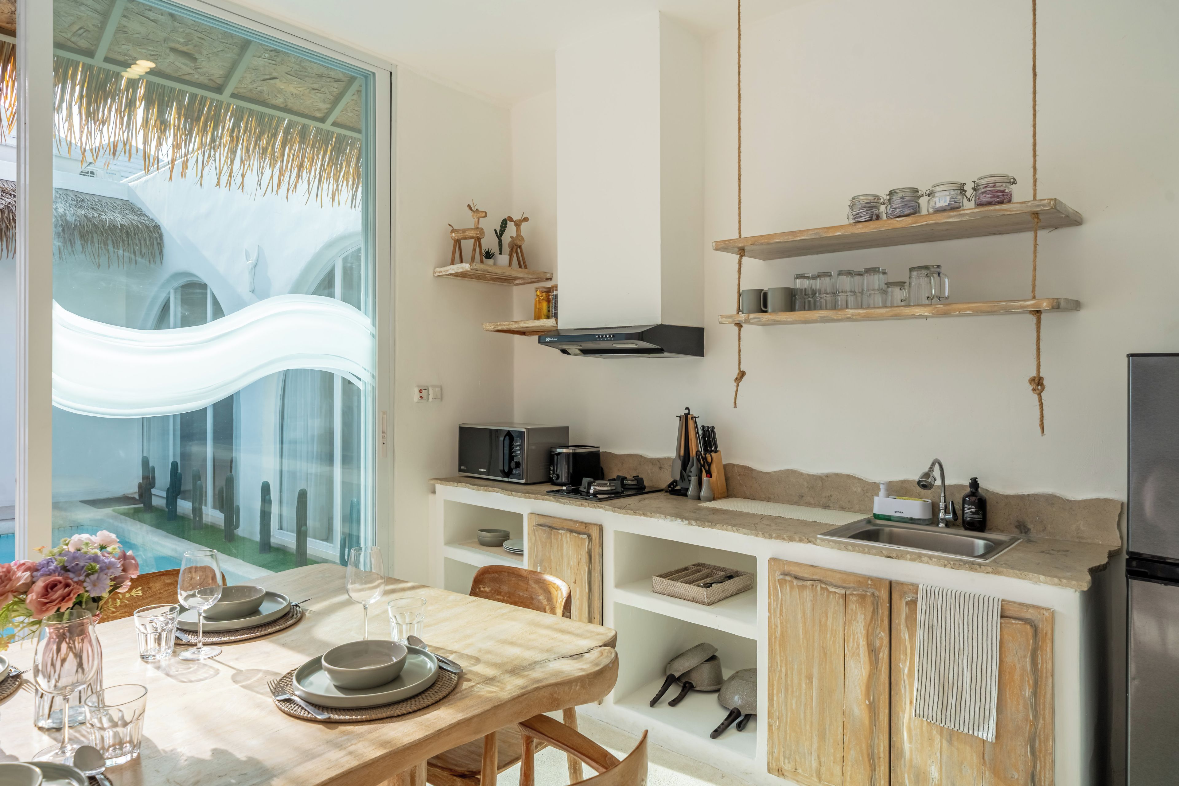 Cozinha moderna com área de refeições, com uma grande janela, prateleiras de madeira e uma ilha central.