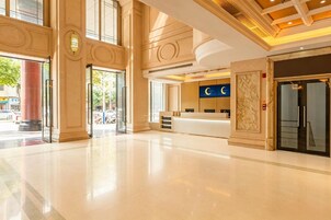 Um hall amplo com balcão de recepção, grandes janelas e piso lustroso.