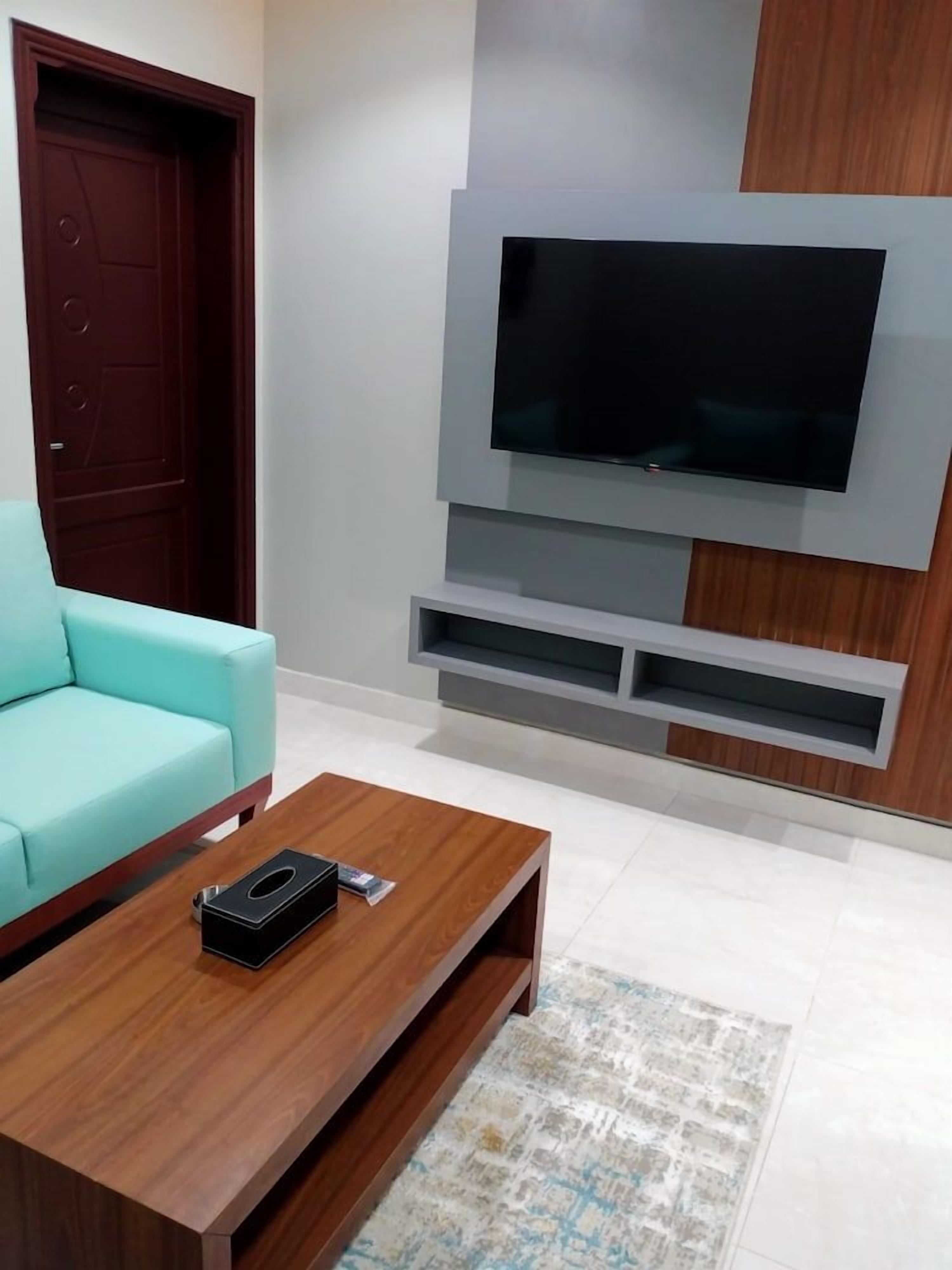 Uma sala de estar com sofá, mesa de centro, televisão de tela plana e estantes embutidas.