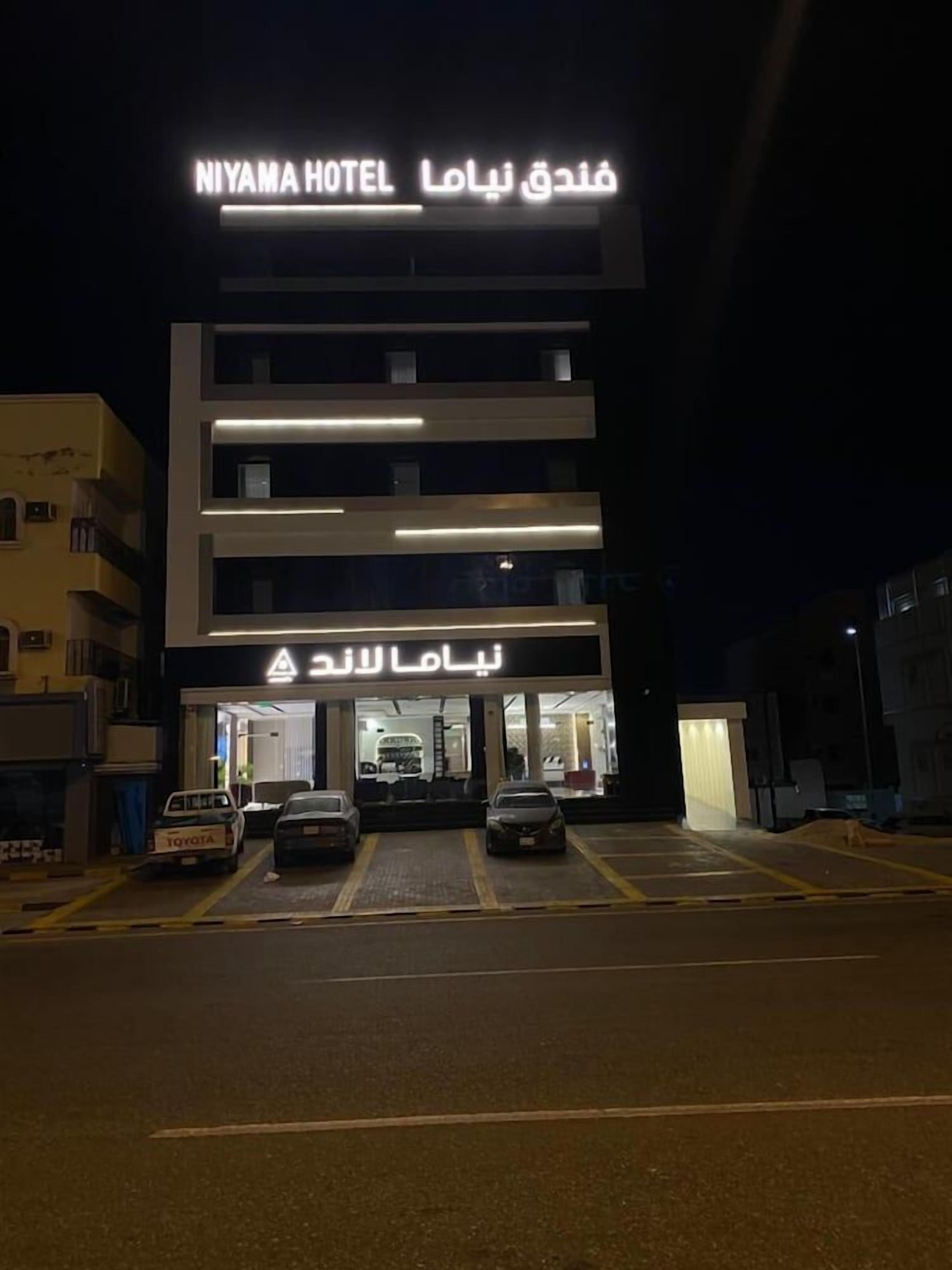 Um hotel com fachada moderna, vários andares e um estacionamento com carros.