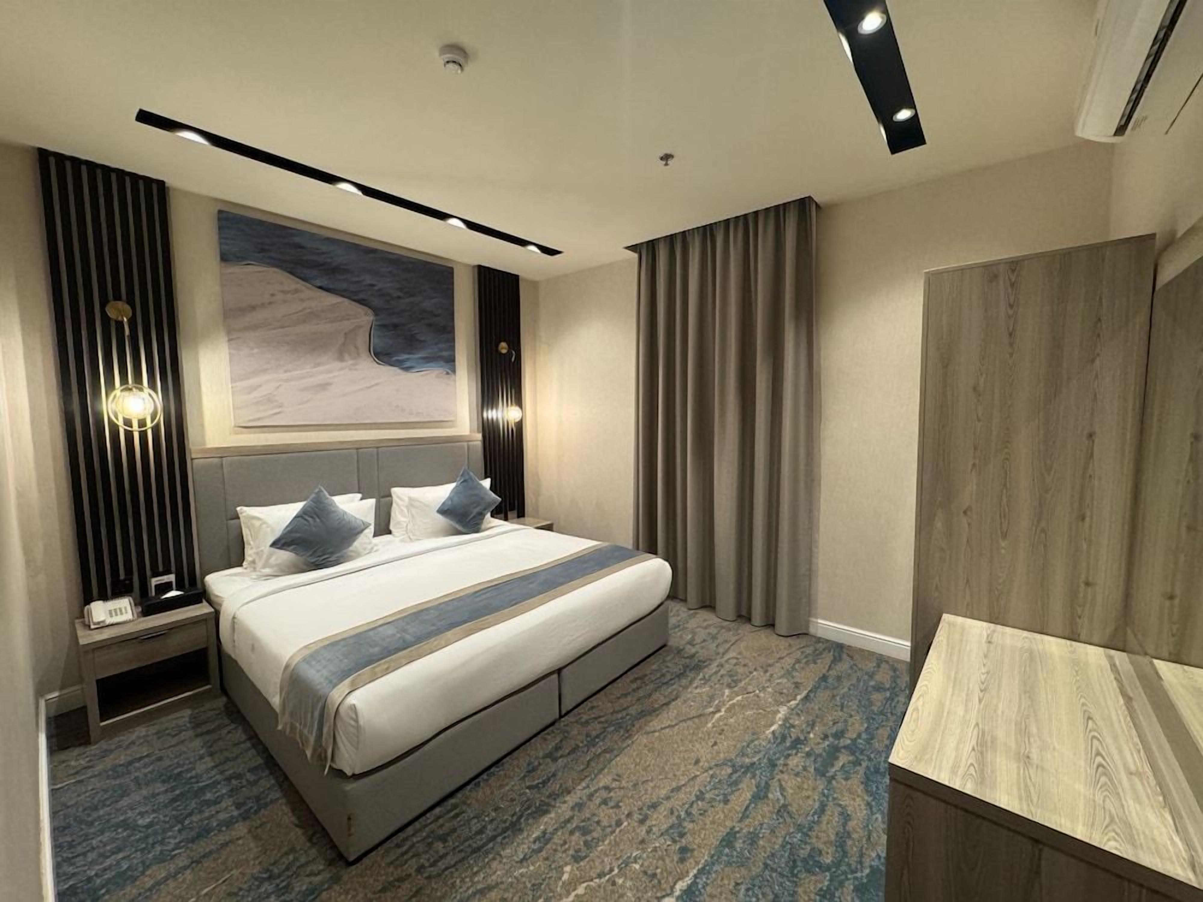 Quarto de hotel moderno com uma cama grande, uma escrivaninha e vista para uma paisagem montanhosa.