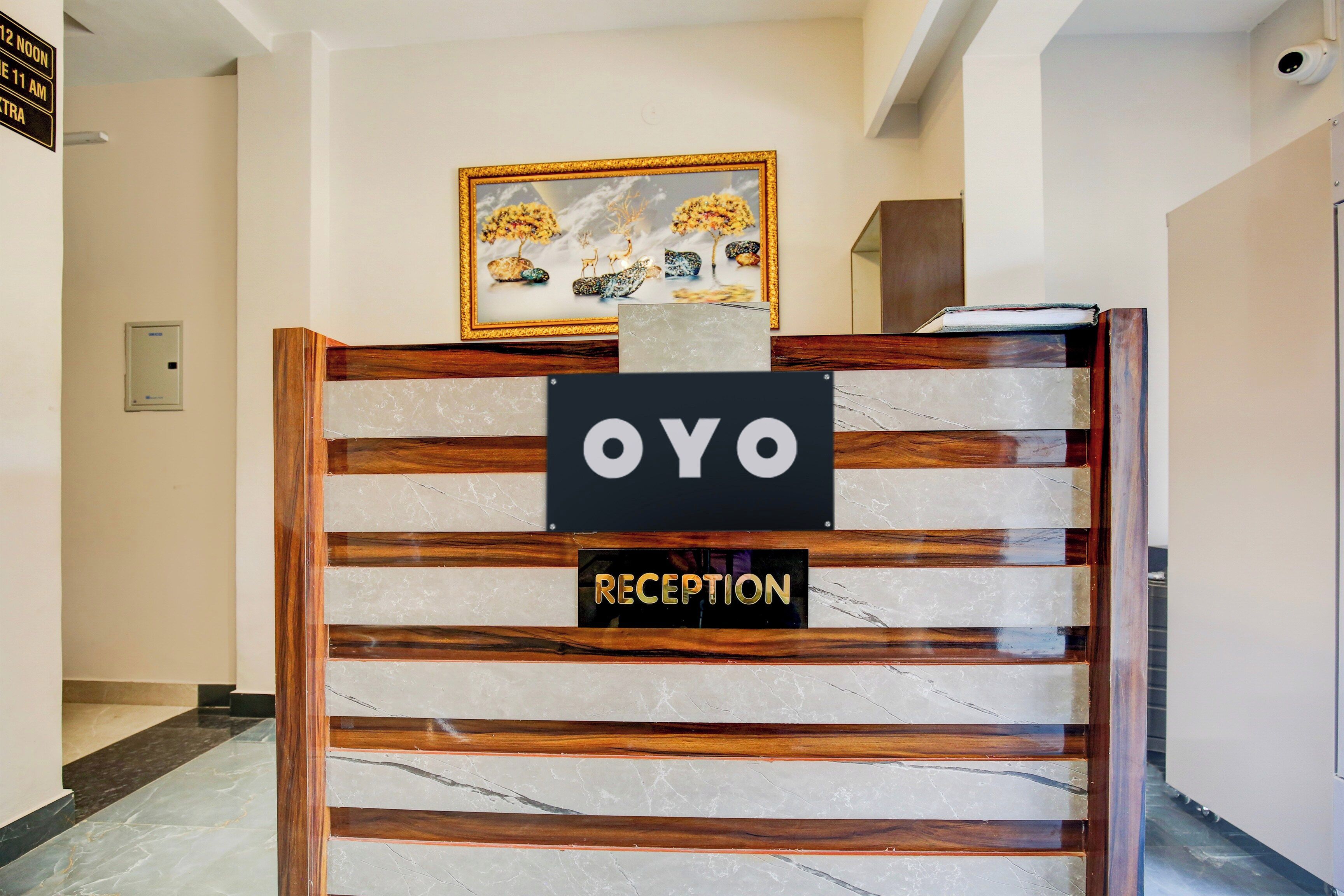 Um balcão de receção com uma placa que diz 'OYO RECEPTION' e uma obra de arte emoldurada acima.