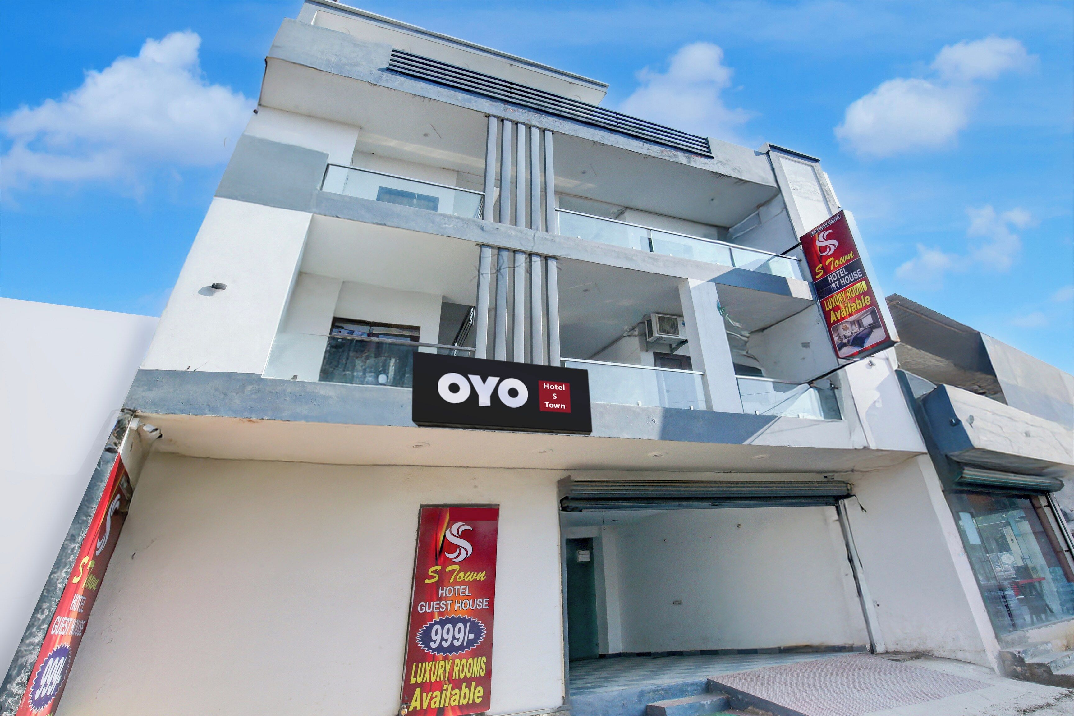 Edifício de hotel com placa indicando 'OYO Hotel Guest House' e 'Quartos de Luxo Disponíveis'.