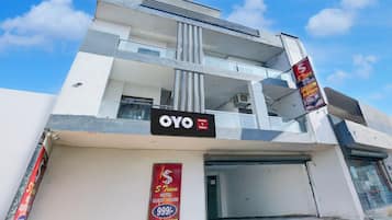 Edifício de hotel com placa indicando 'OYO Hotel Guest House' e 'Quartos de Luxo Disponíveis'.