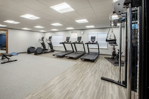 Sala de ginástica com esteiras, elípticos e remo.