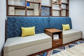 Quarto com sofá, mesa lateral de madeira e parede com padrão.