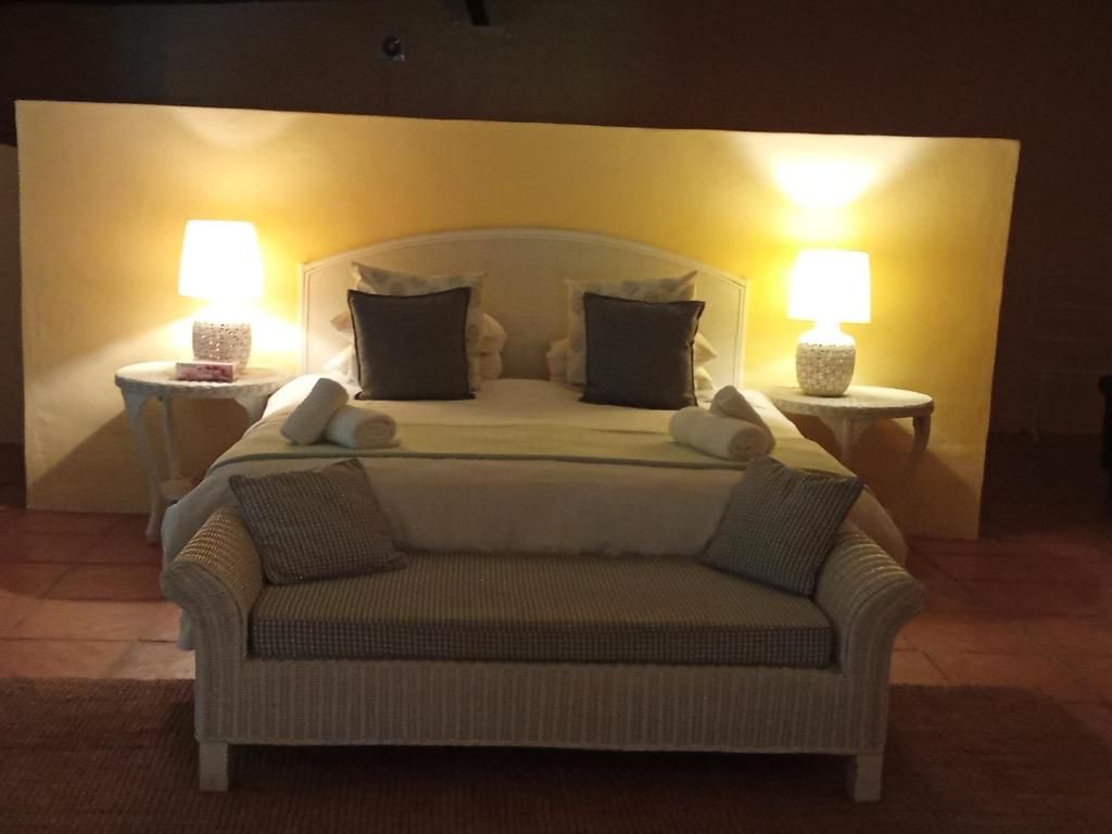 Quarto de hotel com cama, duas luminárias de cabeceira, um sofá e uma cabeceira.