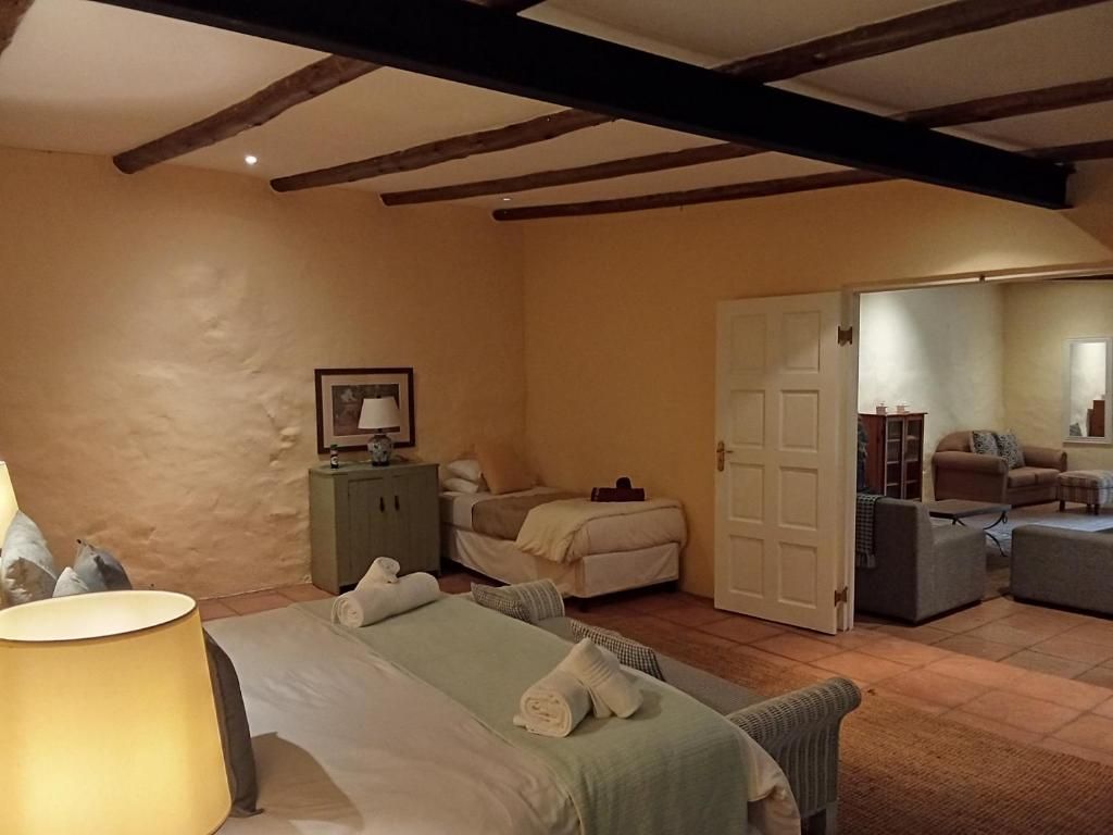 Quarto com cama, mesa de cabeceira, abajur e porta para outro cômodo.